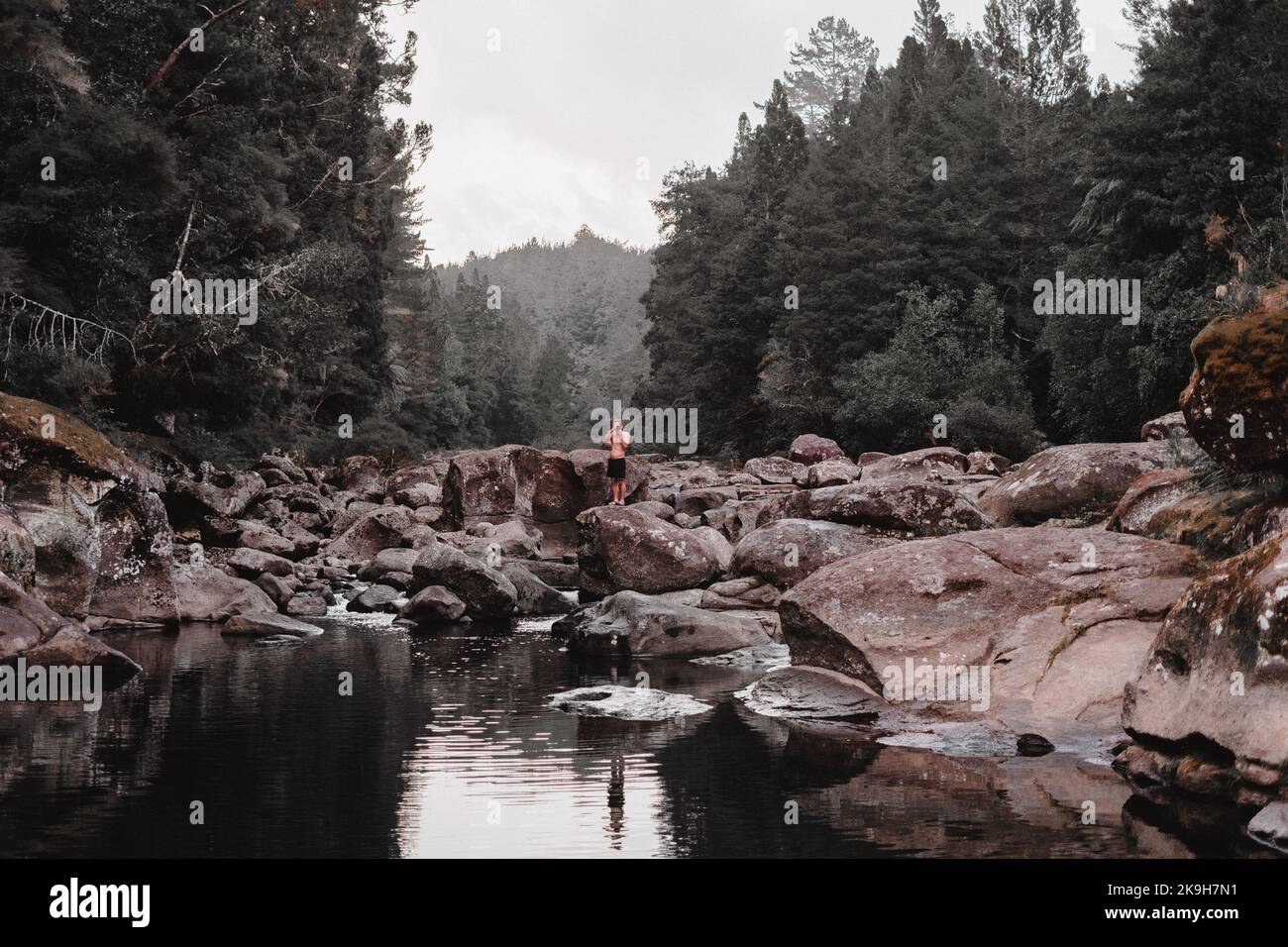 young man taking a photo from a big rock in the river Stock Photo - Alamy
