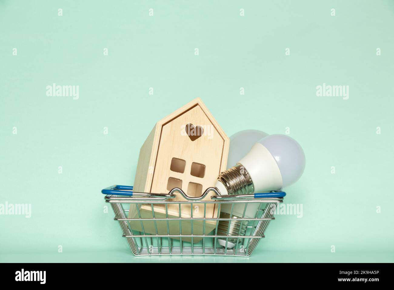 Two led light bulbs and a small wooden house lie in a basket from a ...