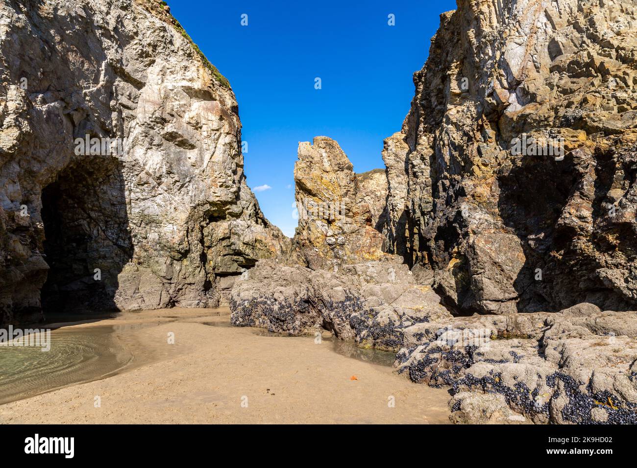 Rock formations and caves on Perranporth beach in Cornwall, with a blue ...
