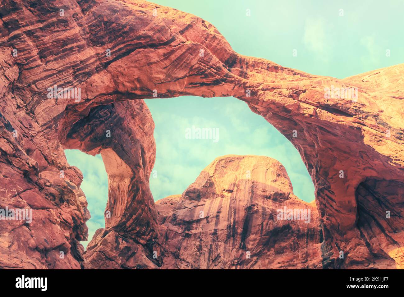 A low-angle shot captures a majestic natural Double Arches, framing a ...