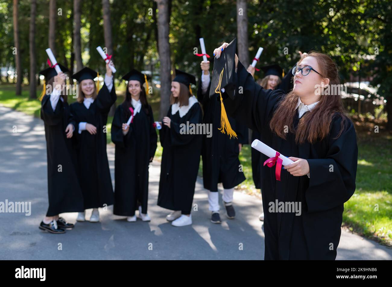 Portrait of a young caucasian woman in glasses and a graduate gown ...