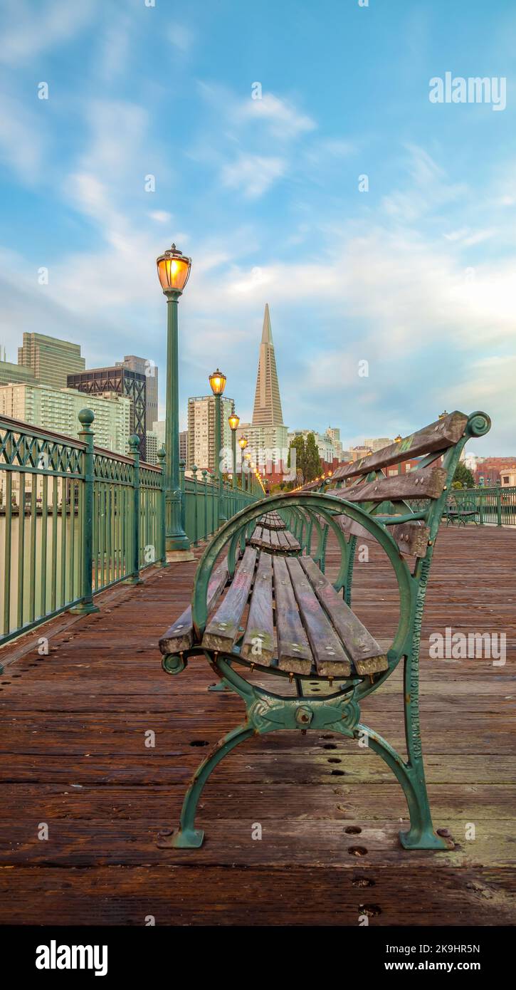 A row of wooden benches with green metal frames line the pier ...