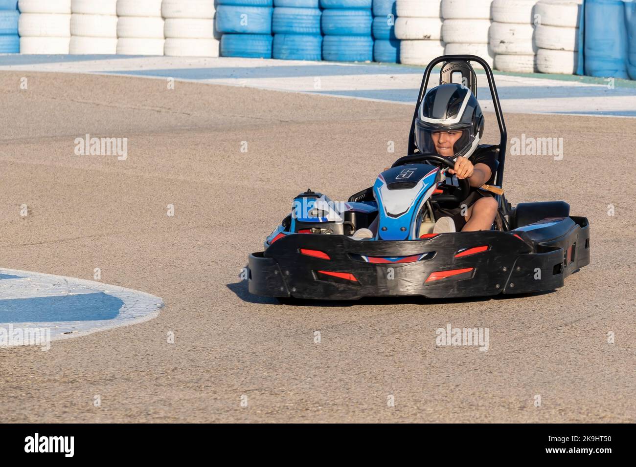 a teenager boy driving a kart at the exit of a curve of a karting ...