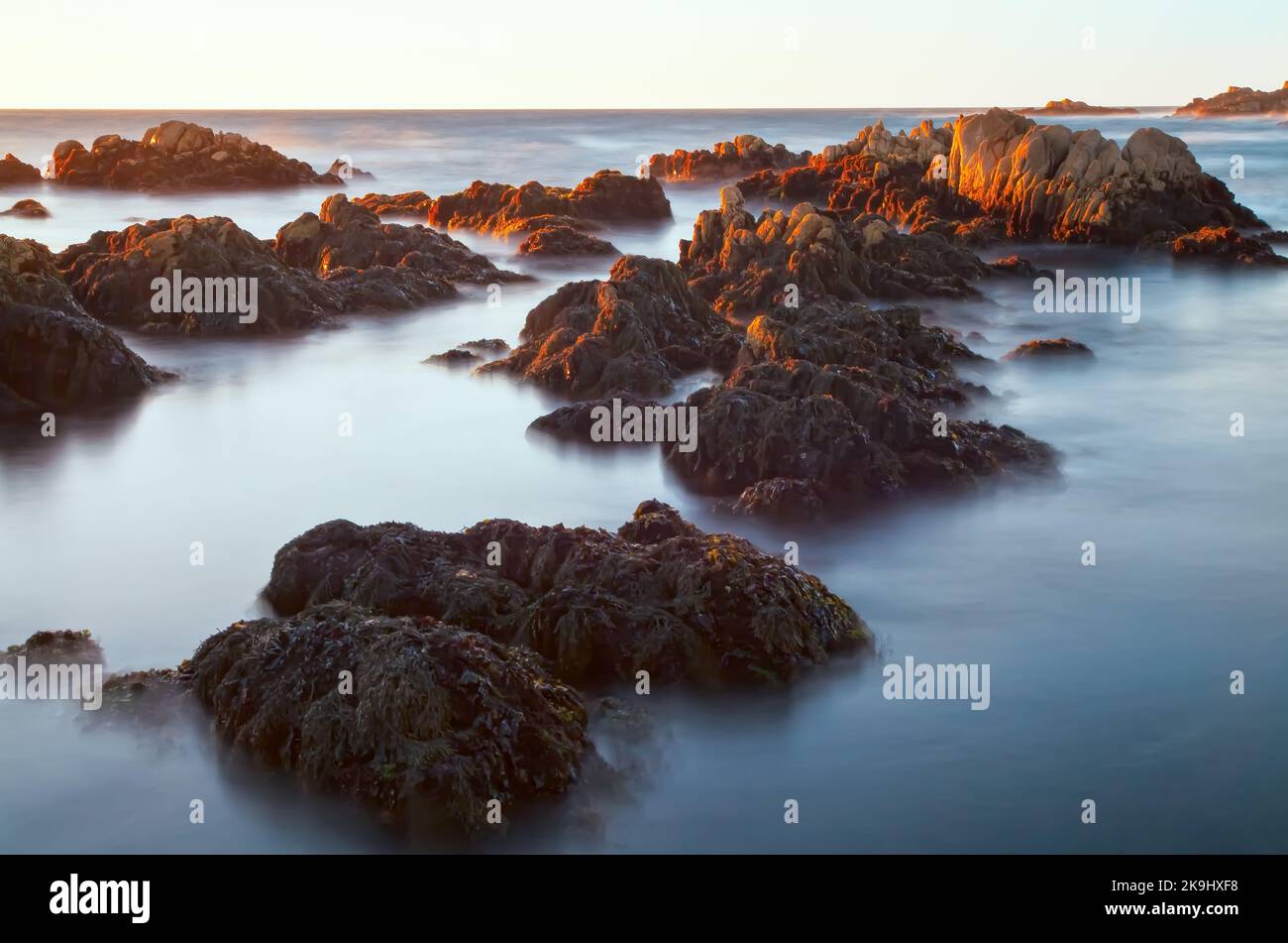 A serene seascape photograph captures a cluster of rugged rocks jutting ...