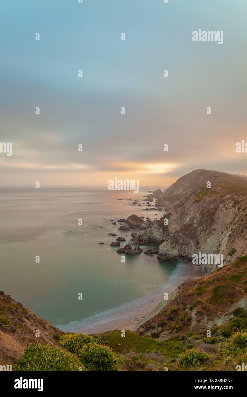 A breathtaking coastal landscape at sunset with rocky cliff jutting out ...