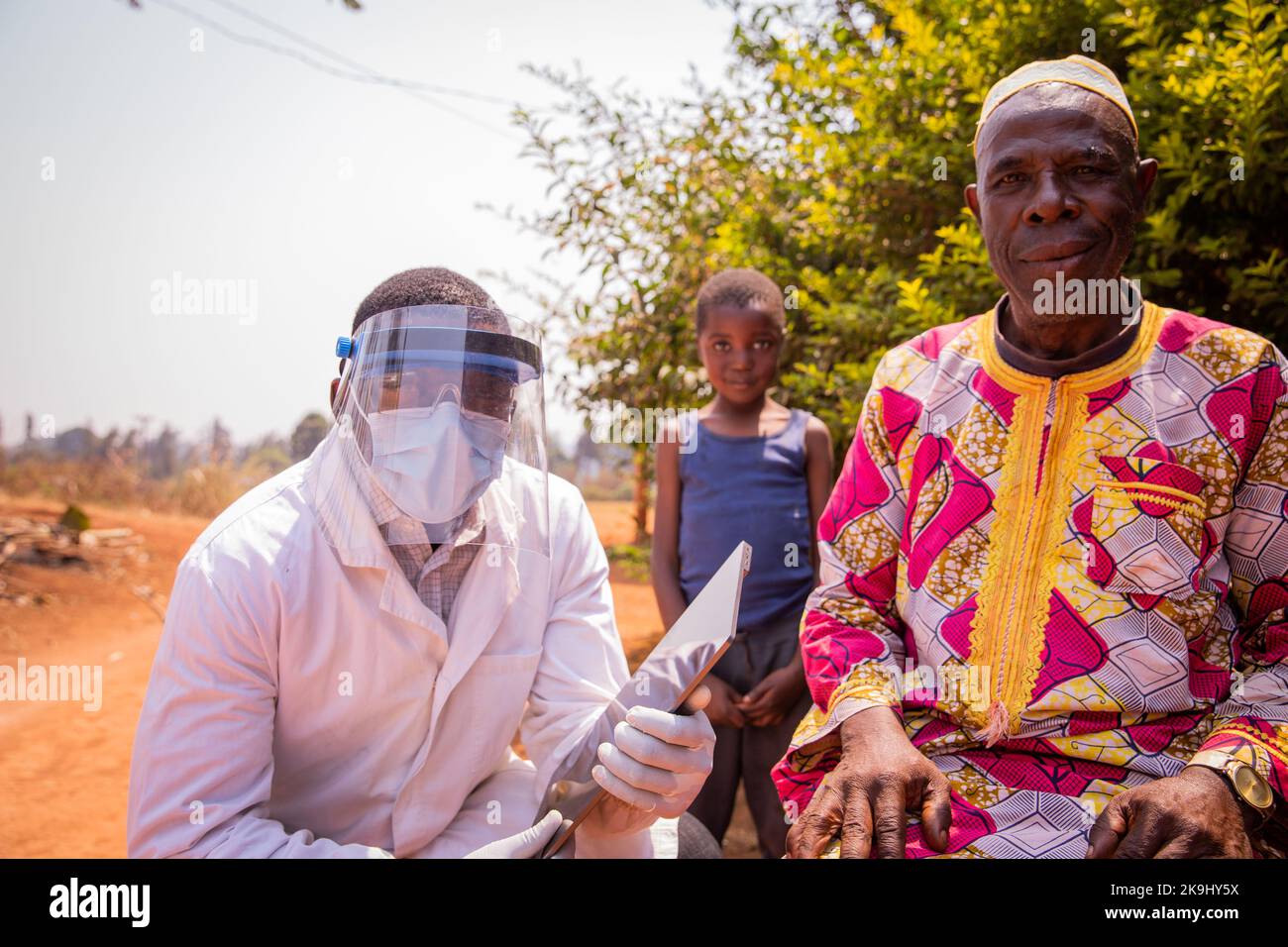 Healthcare worker posing with an elderly person and a child in full ...
