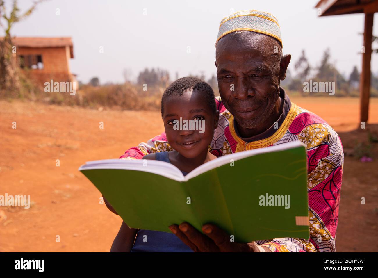 African grand father educating his grandson outdoor under the sun ...