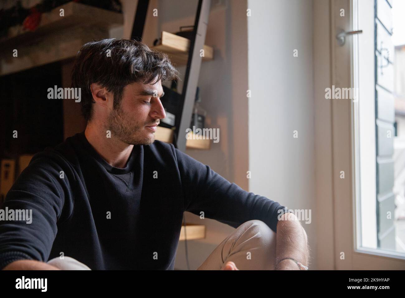 Concentrated man in his 30s seated on the floor with eyes closed ...