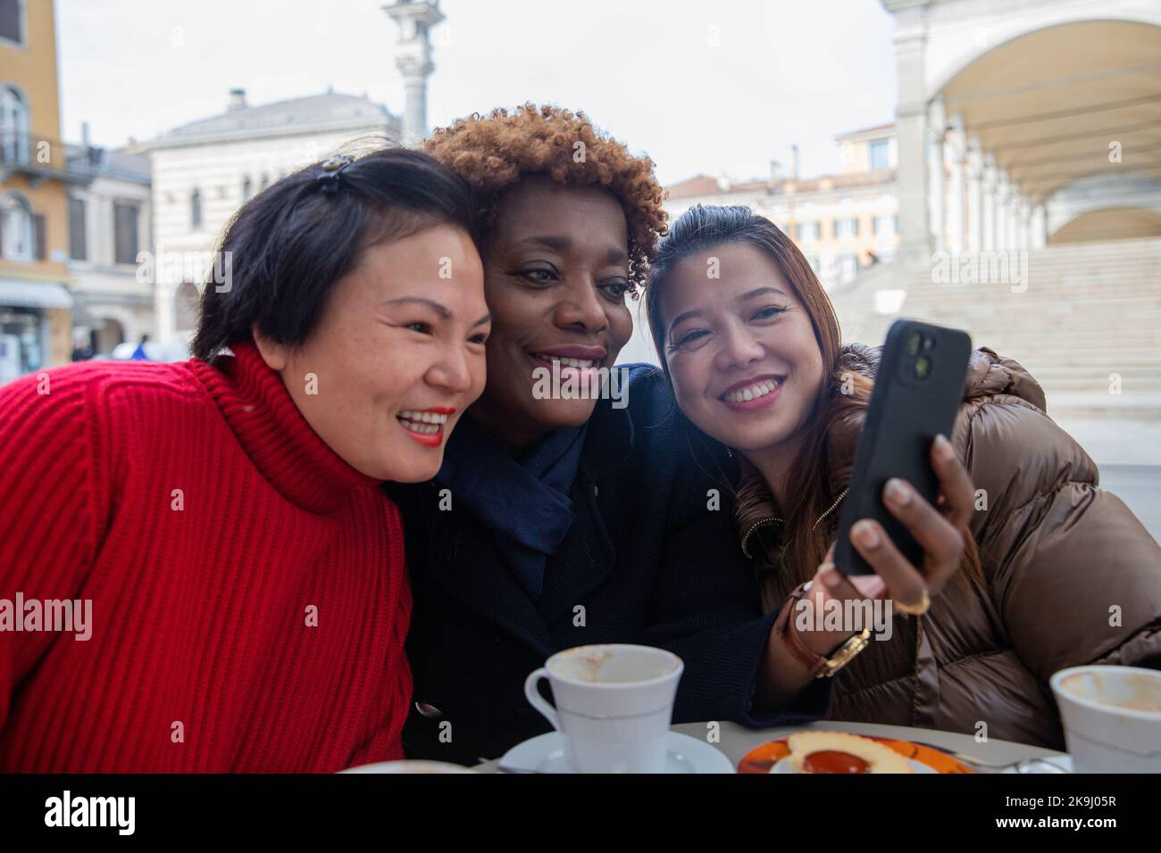 Smiling friends having fun sharing something on the mobile phone ...
