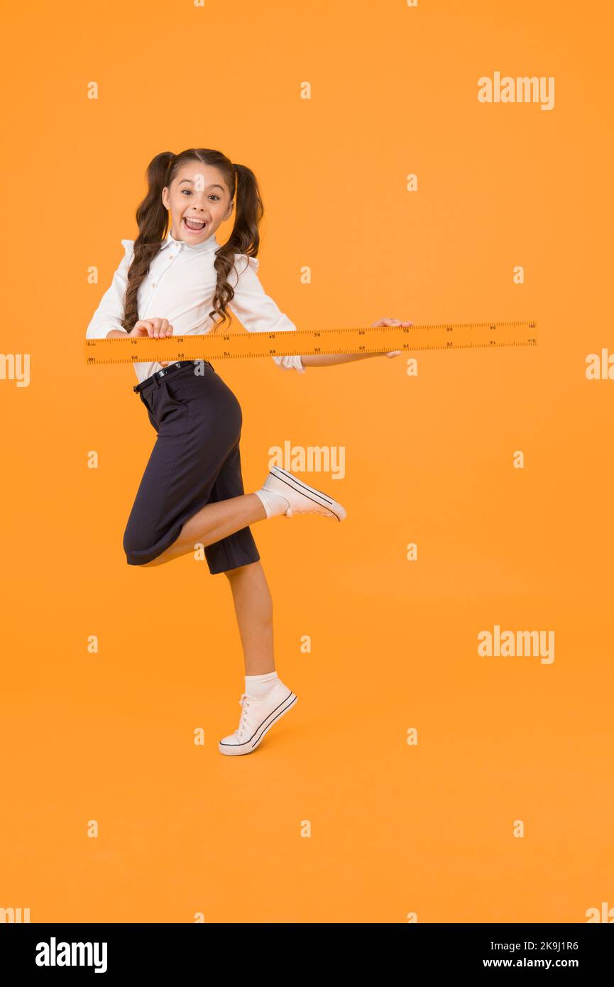 She is in a hurry to lesson. Energetic schoolchild holding long ruler ...