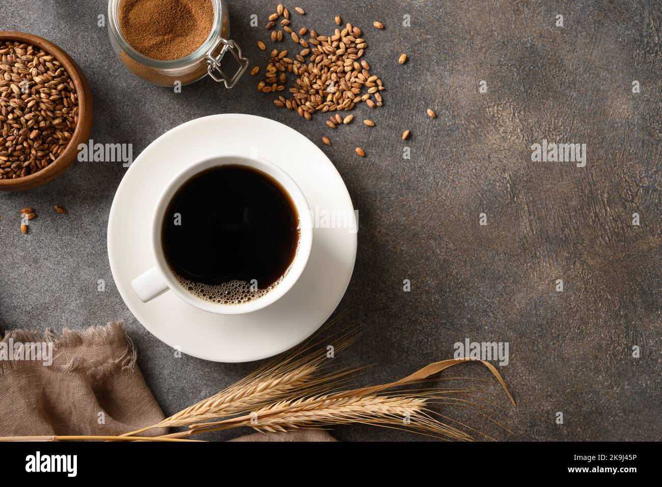 Barley coffee in white cup, beans and ears of barley on brown ...