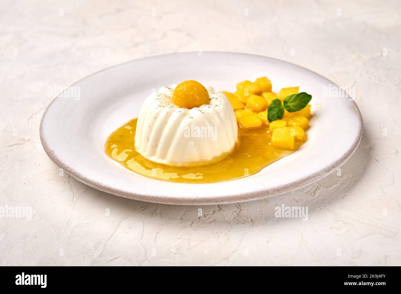 Homemade panna cotta with natural vanilla pod, mango syrup and mint ...