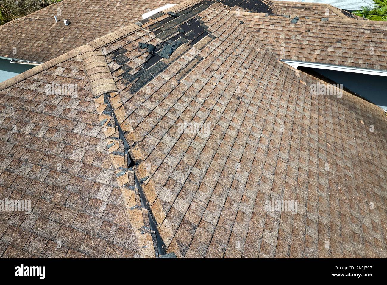 Wind damaged house roof with missing asphalt shingles after hurricane ... Wind damaged house roof with missing asphalt shingles after hurricane ...