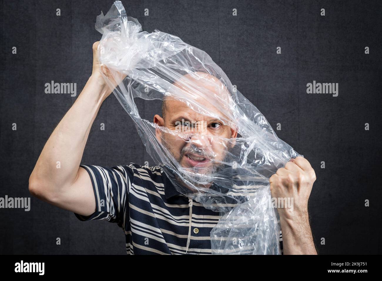 Mature man with a transparent plastic bag flying over his head and face ...