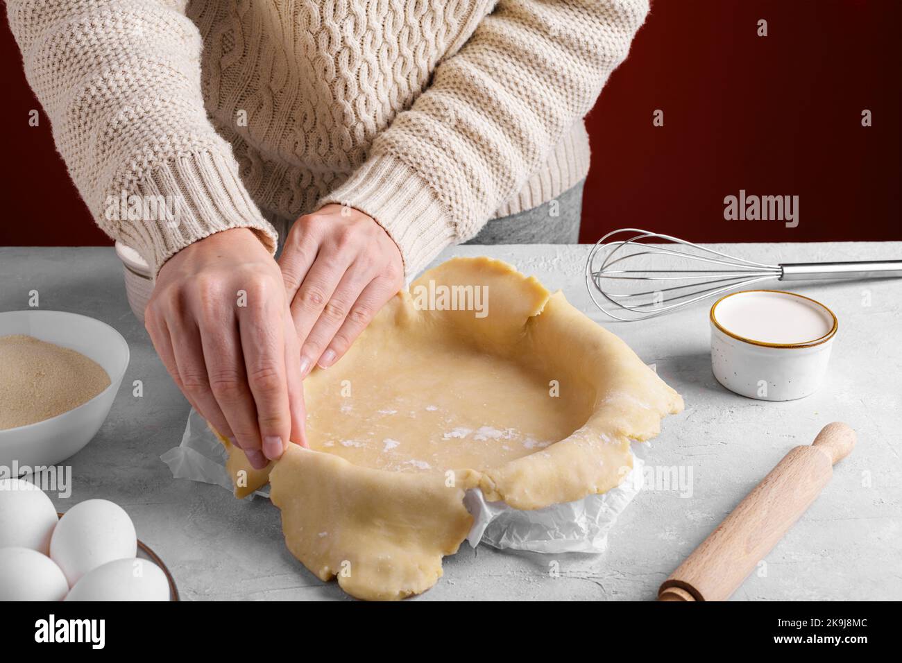 Woman arranging the dough in the pie pan on the table in the kitchen ...