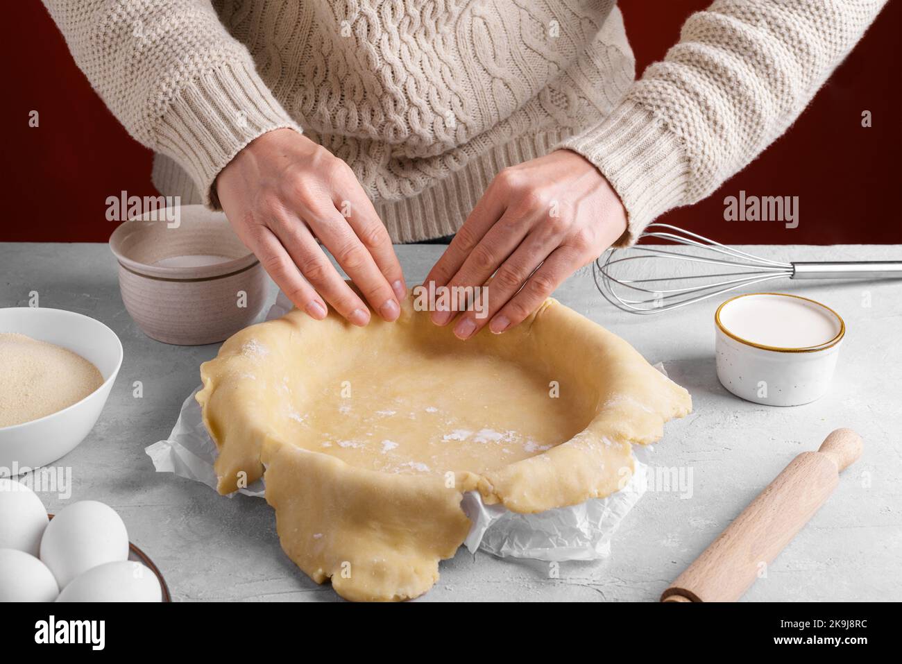 Woman arranging the dough in the pie pan on the table in the kitchen ...