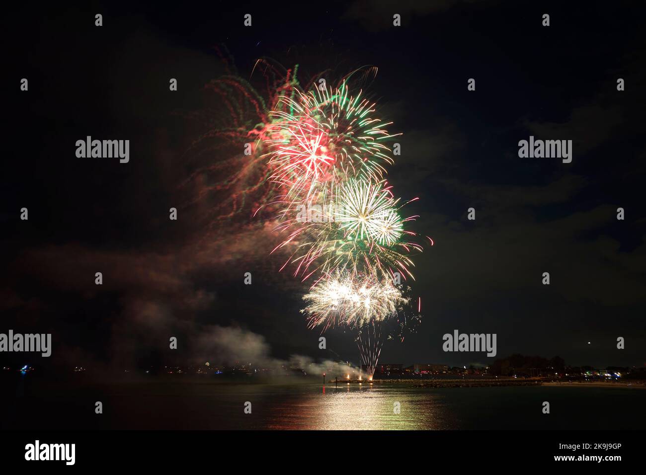 Aerial view of bright fireworks exploding with colorful lights over sea ...