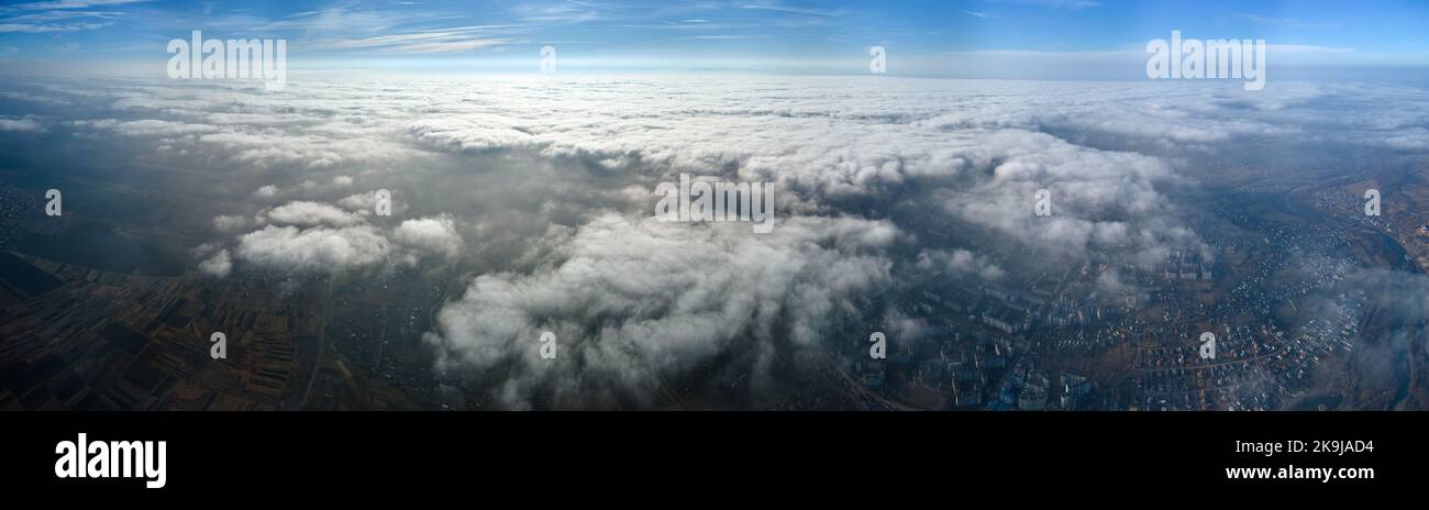 Aerial view from high altitude of distant city covered with puffy ...