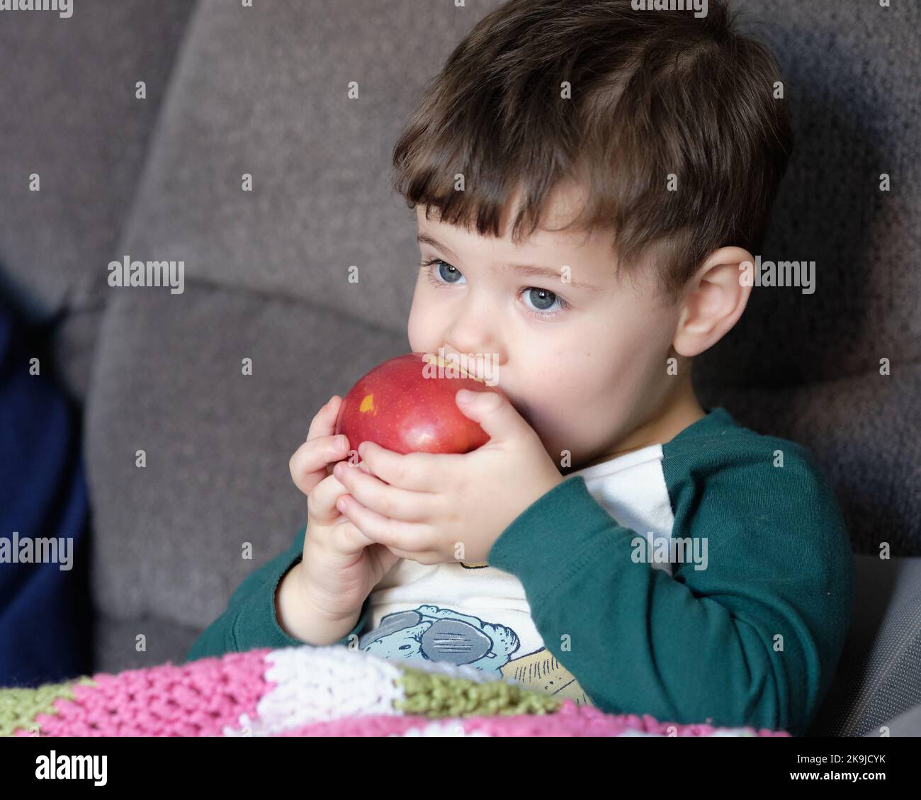 young boy eating apple on the couch Stock Photo - Alamy