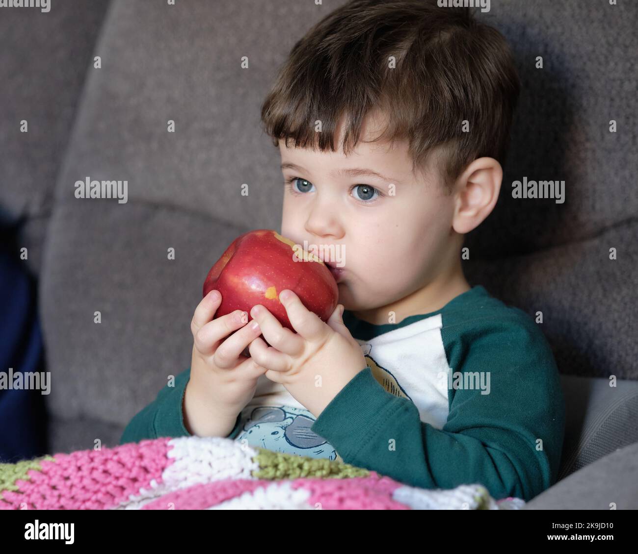 young boy eating apple on the couch Stock Photo - Alamy