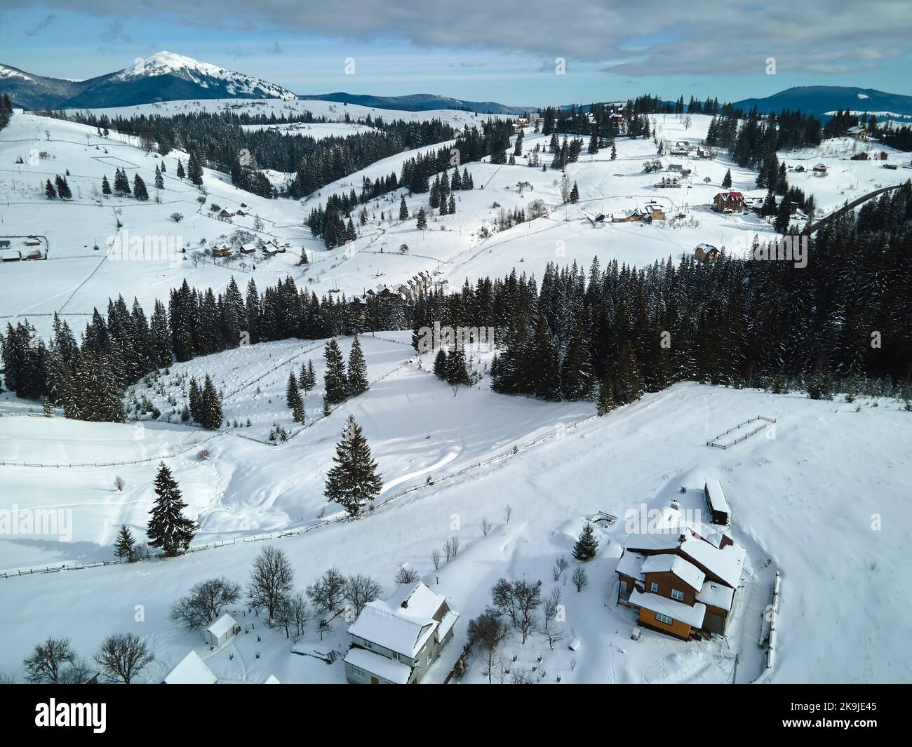 Winter landscape with small village houses between snow covered forest ...