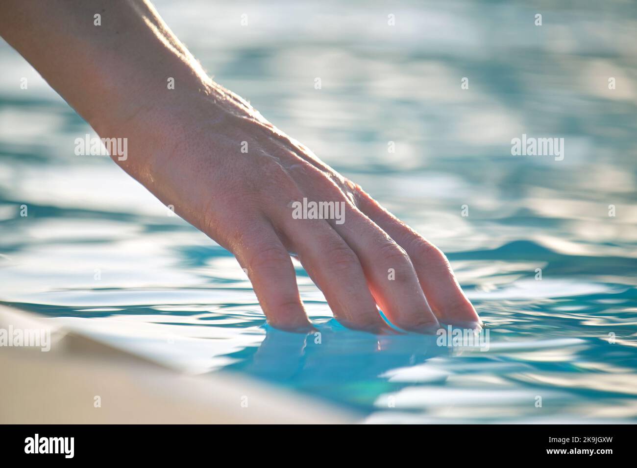 Female hand touching water of swimming pool in summer Stock Photo - Alamy