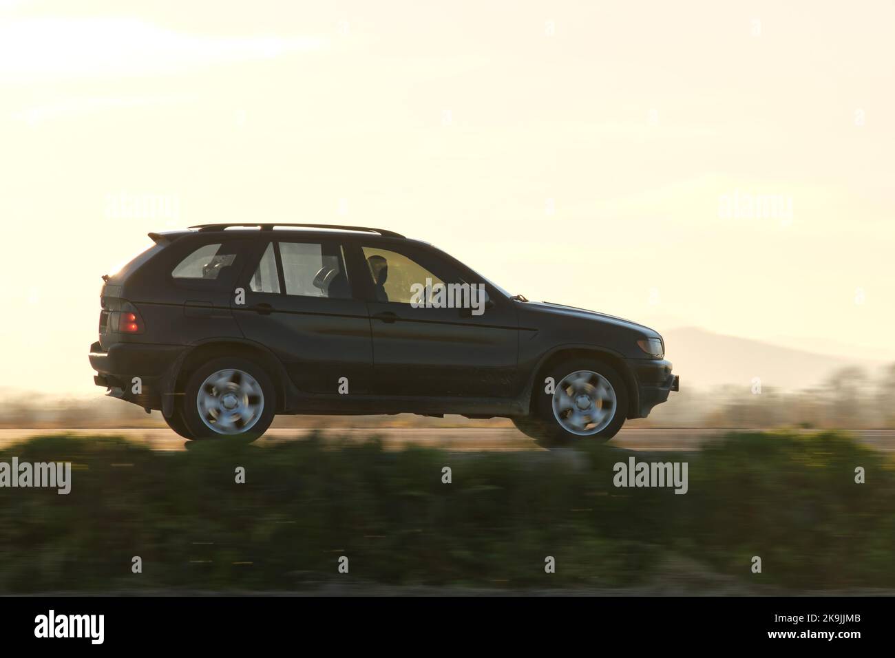 SUV car driving fast on intercity road at sunset. Highway traffic in ...