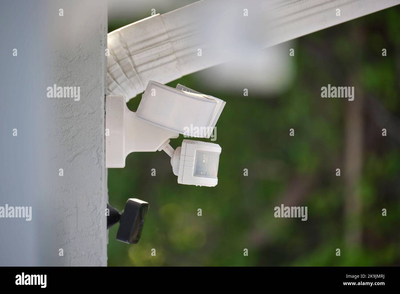 Motion sensor with light detector mounted on exterior wall of private ...