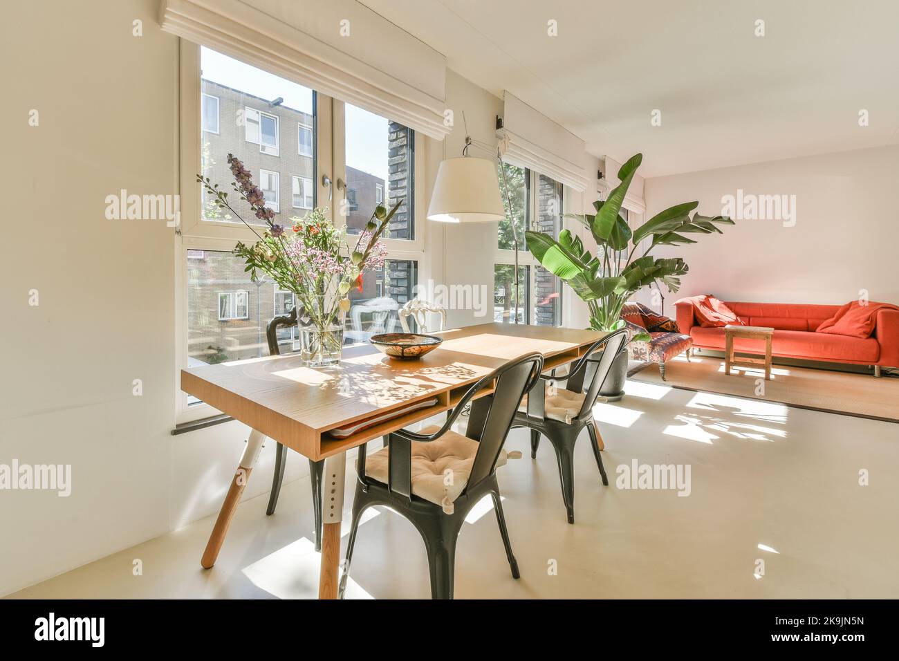 Table with chairs and flowers located near lounge area and kitchen in ...