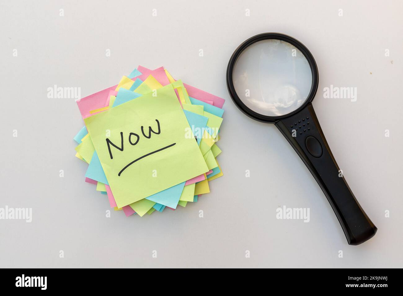 hand written word NOW on sticky paper note on a white isolated ...