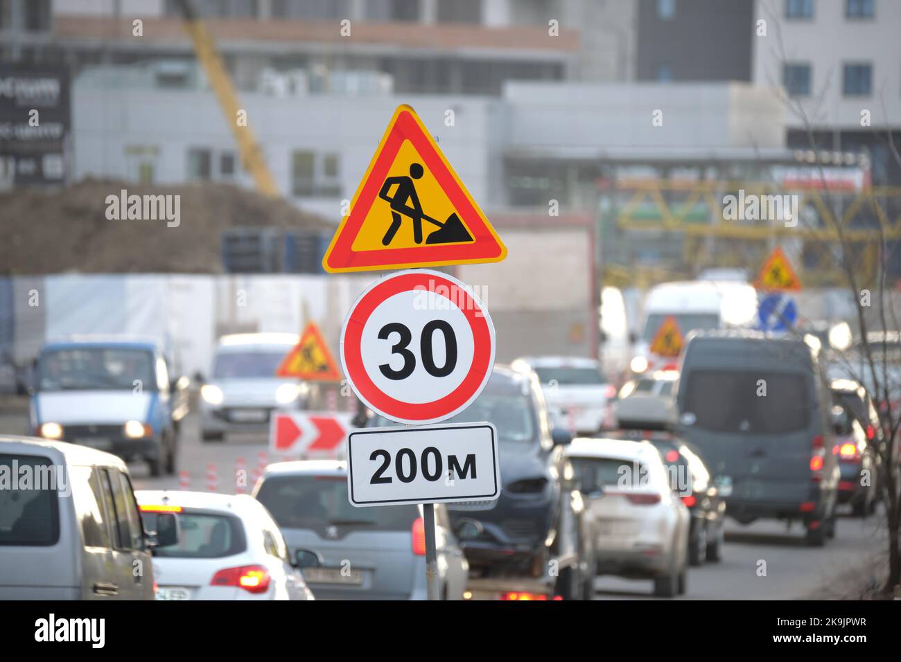Roadworks warning traffic signs of construction work on city street and slowly moving cars Stock ...