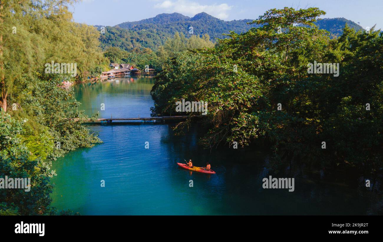 A couple of men and women are Kayaking in the rainforest of Koh Chang ...