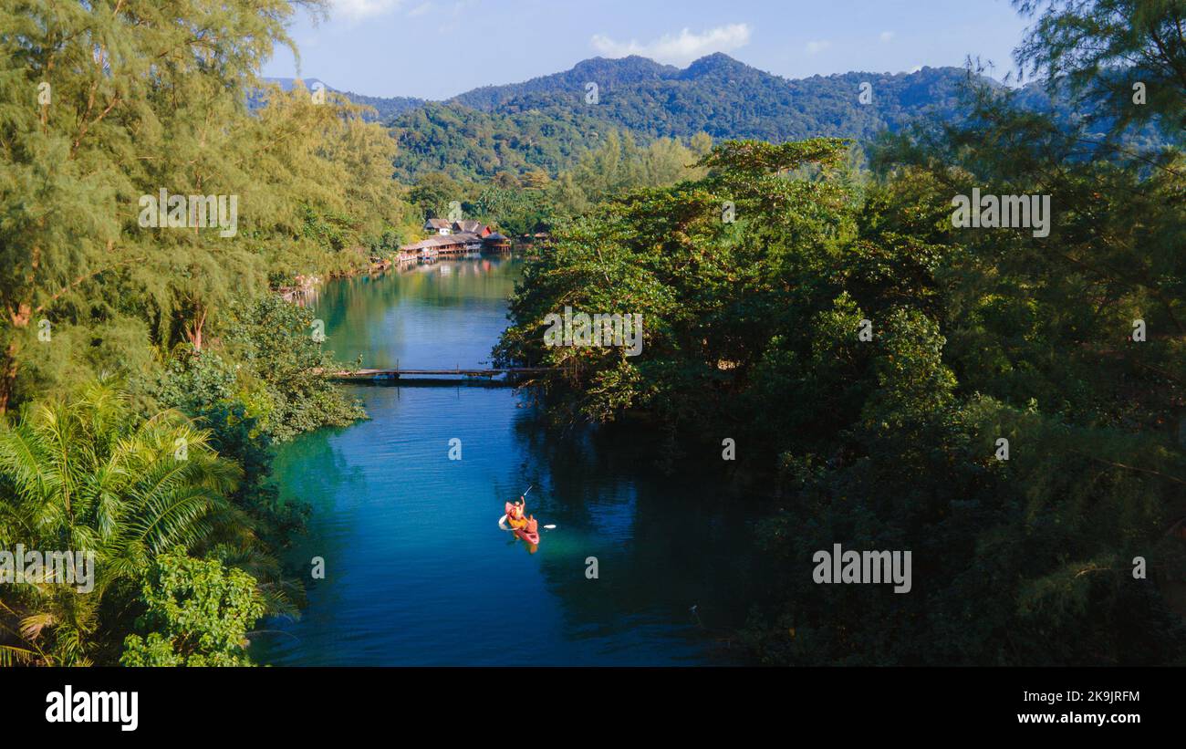 A couple of men and women are Kayaking in the rainforest of Koh Chang ...