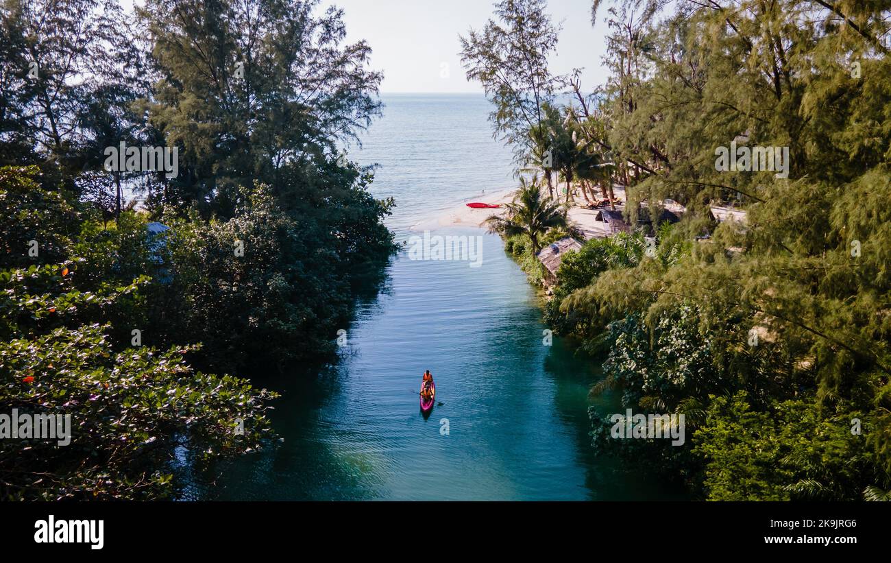 A couple of men and women are Kayaking in the rainforest of Koh Chang ...