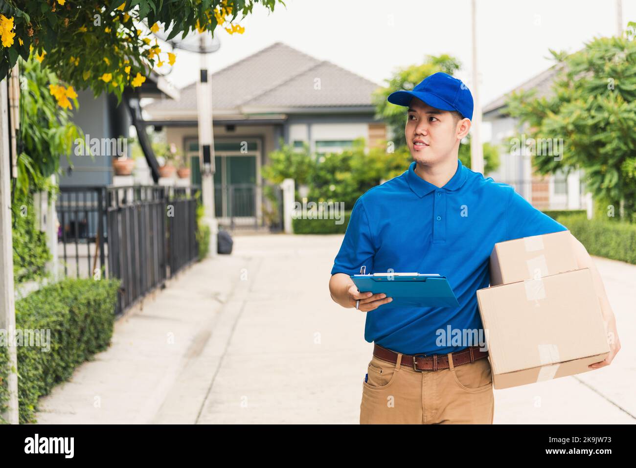 Asian young delivery man courier in uniform hold parcel post boxes ...