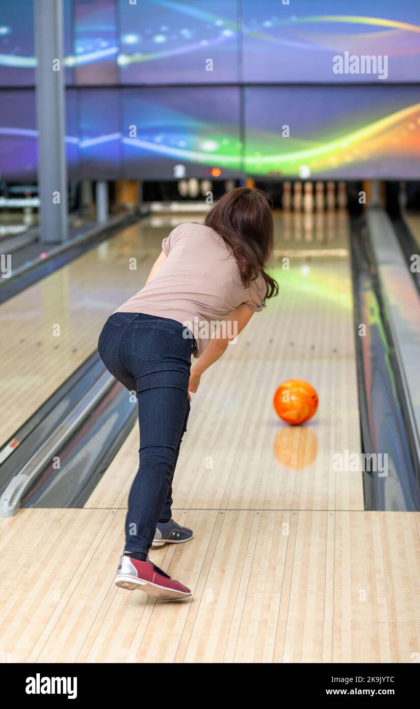 A woman throws a ball into a bowling alley. Paths with balls and pins ...