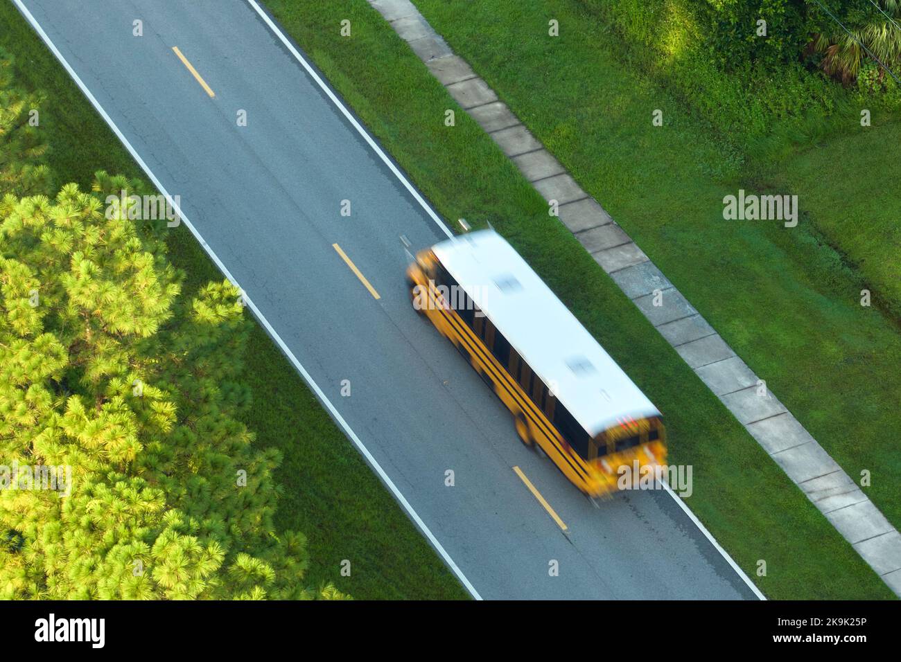 Aerial view of american yellow school bus driving on suburban street ...