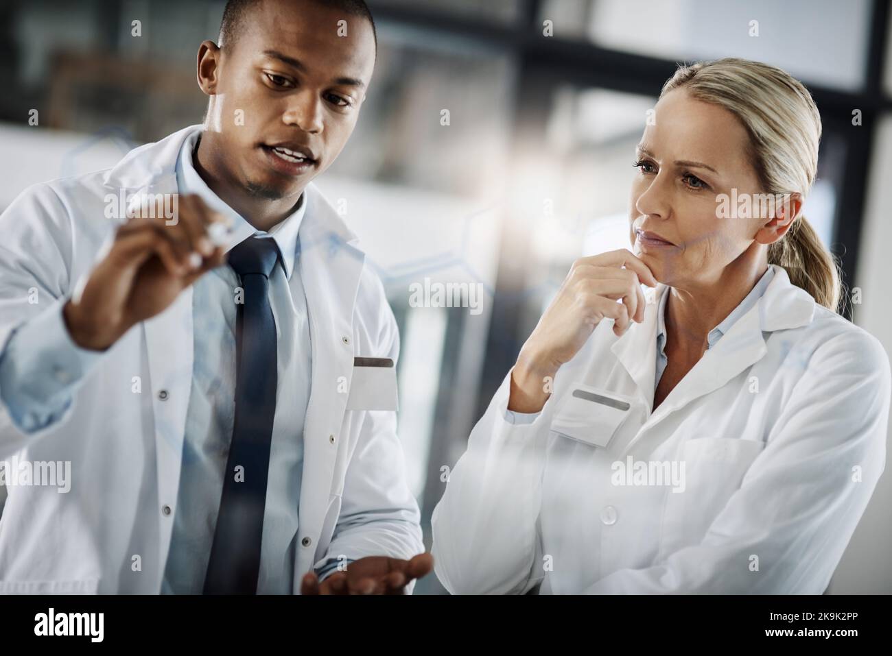 Its all in the formula. two scientists writing down formulas on a glass ...