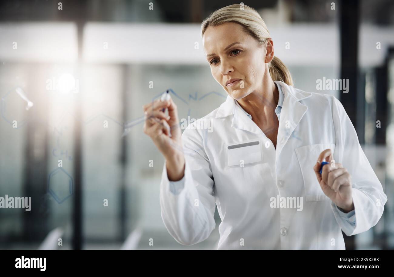 Her mind is working. an attractive mature female scientist writing down ...