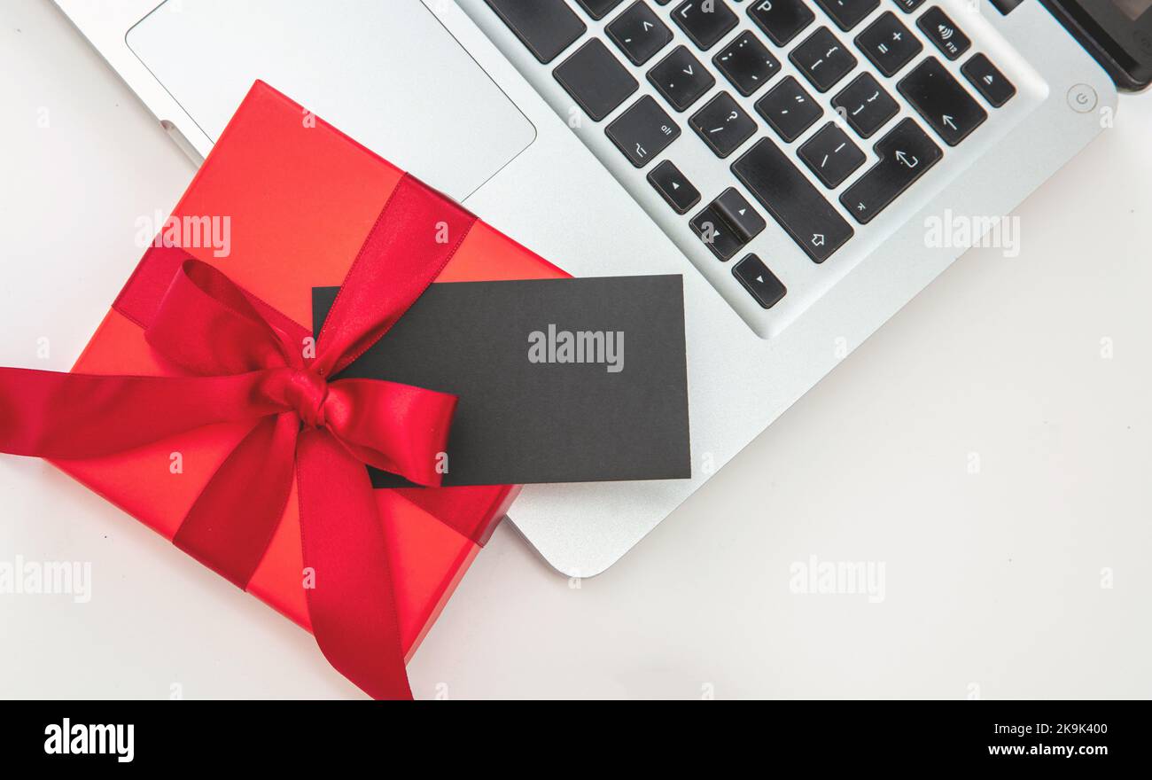 Red gift box and black card on a computer laptop, white background, top ...