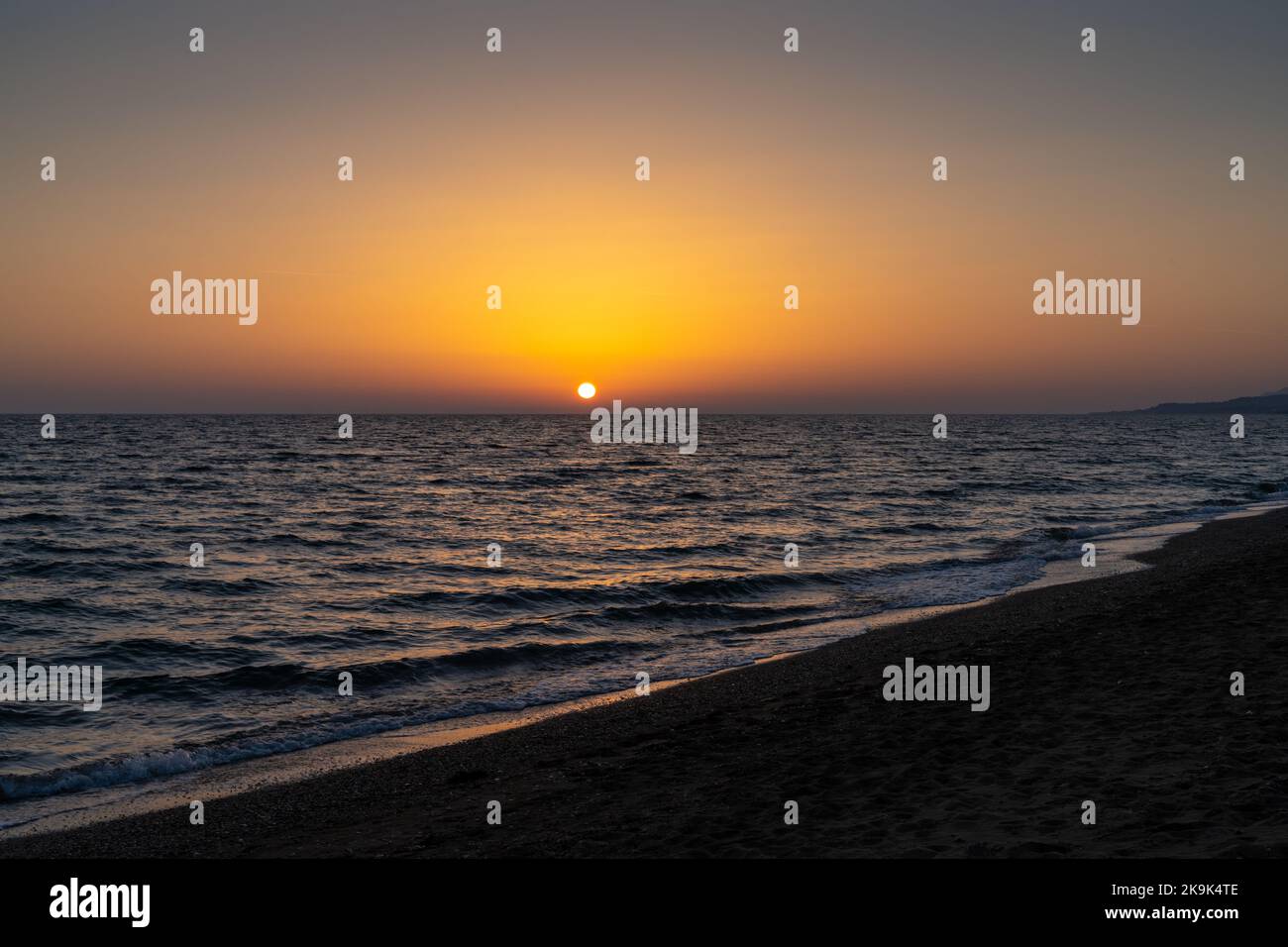 colorful sunset on the Mediterranean Sea in Greece with calm ocean ...