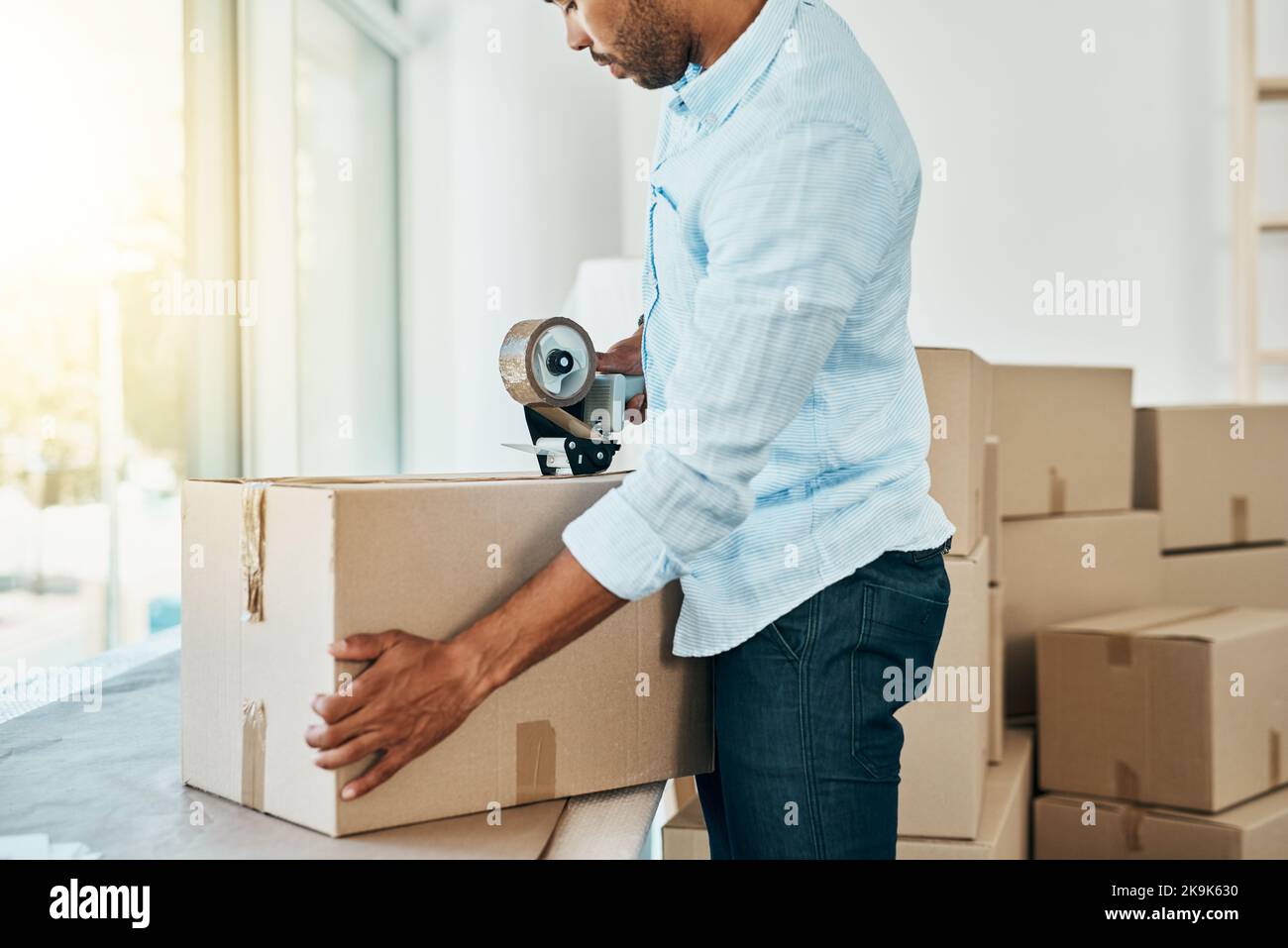These are the last of the boxes. Shot young man sealing a box while ...