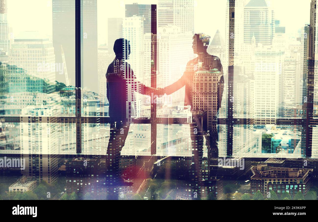 Merge and make it work. two young businessmen shaking hands ...