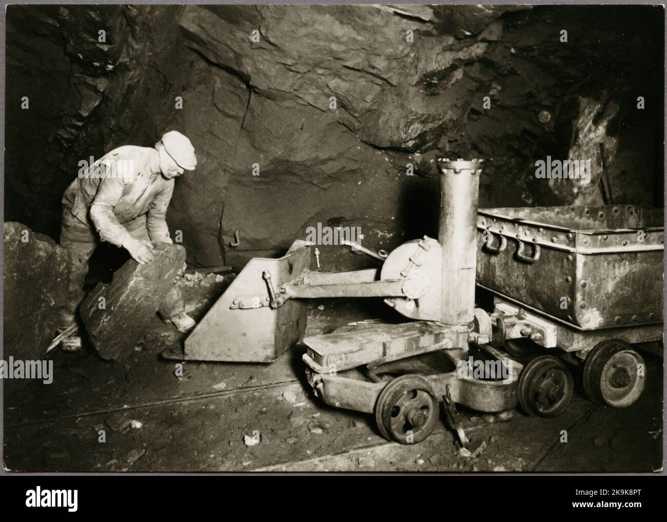 Miners load a boulder on a compressed air -powered loading machine ...