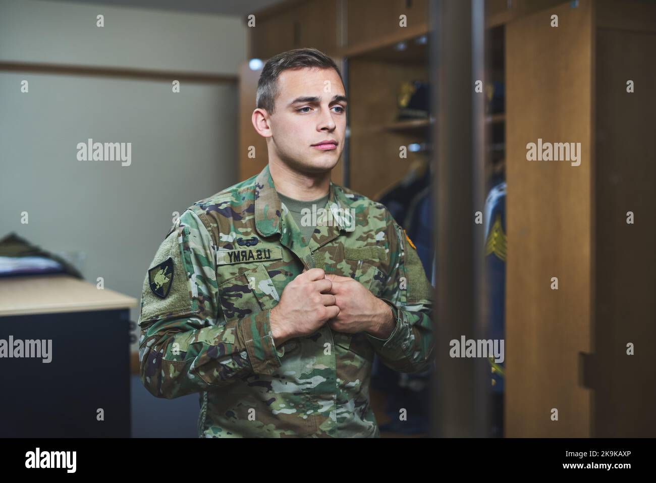 Mornings in the military. a young soldier standing getting dressed in ...