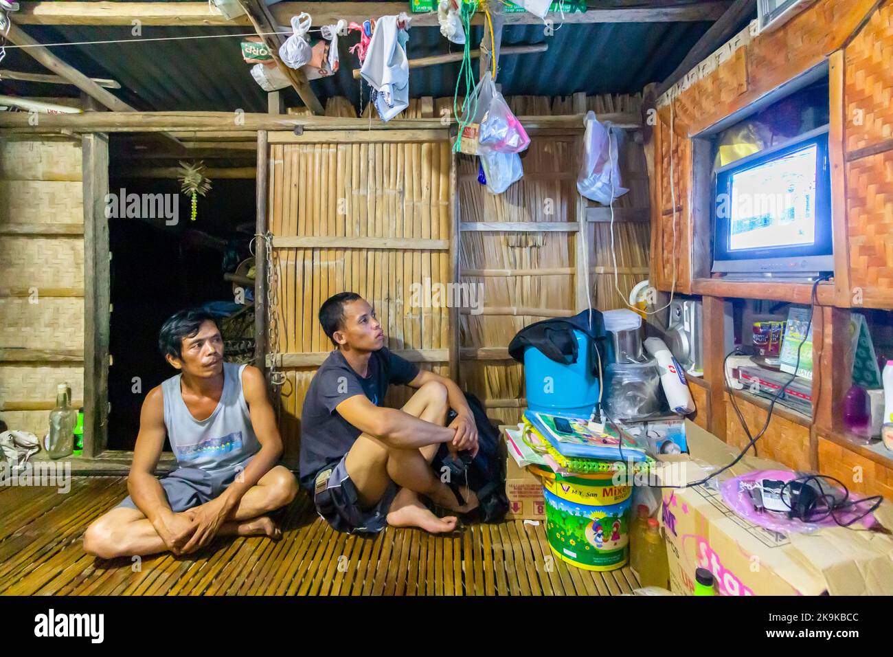 Two Filipino men watching TV at their native house in Batangas ...