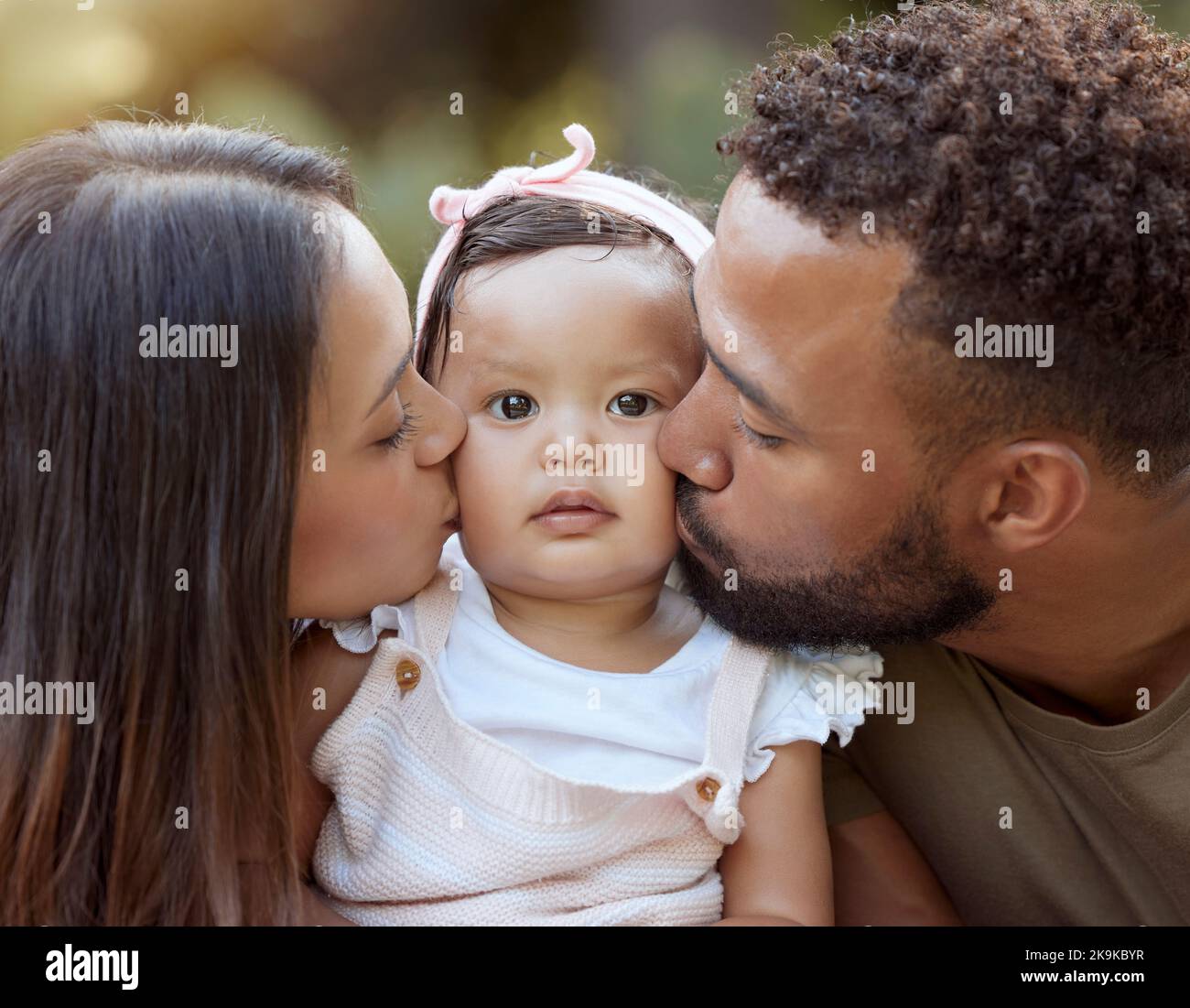 Mother, father and baby face kiss while bonding in a garden outdoors ...