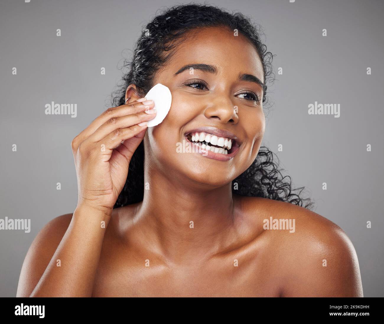 Skincare, cotton pad and woman cleaning face with a smile against a ...
