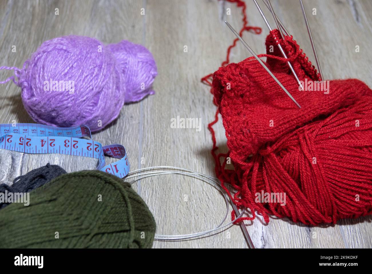 Sock in the process of knitting with needles and yarn of red color on a ...