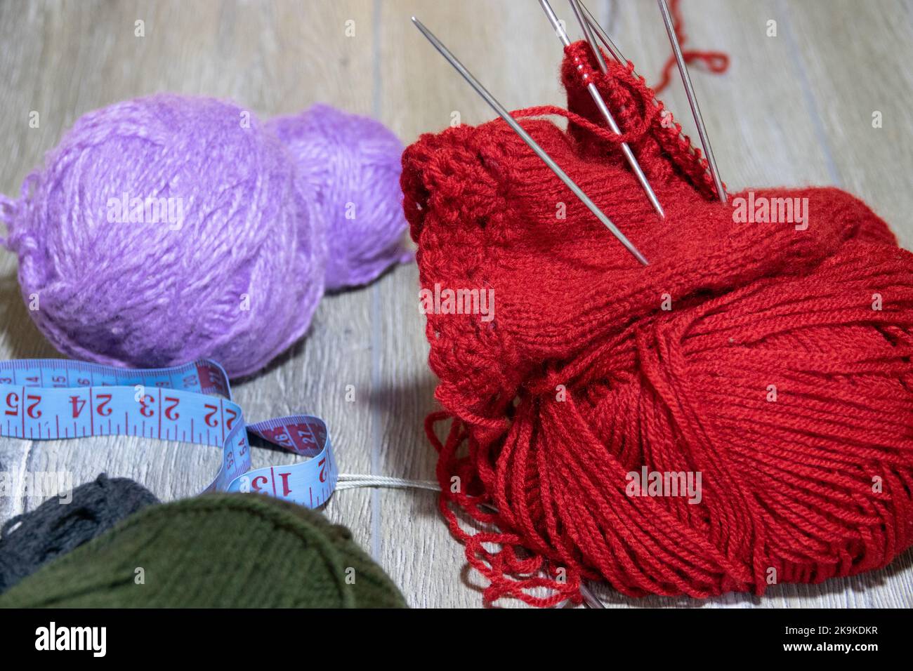 Sock in the process of knitting with needles and yarn of red color on a ...